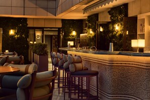Uma área de bar com balcão, banquetas e iluminação ambiente.