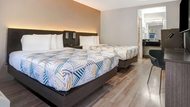 Quarto de hotel com uma cama grande, uma escrivaninha e um espelho.