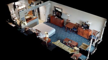 Quarto de hotel com cama, escrivaninha, cadeira, televisão, cómoda e banheiro.