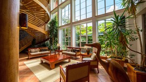 Um interior espaçoso com escada de madeira, amplas janelas e diferentes opções de assentos.