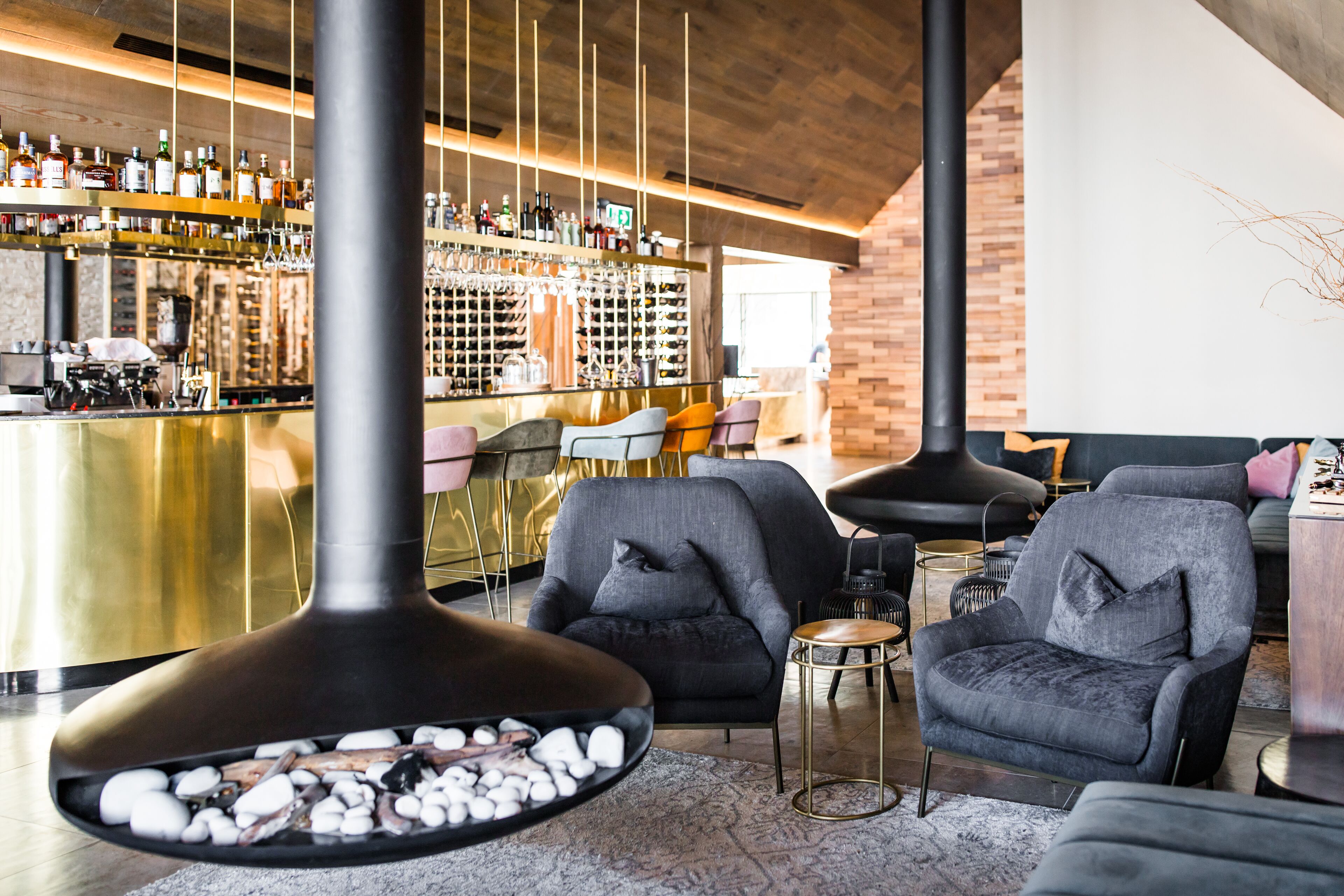 Uma área de bar moderna com diversas garrafas de bebidas, um balcão e assentos com lareira.