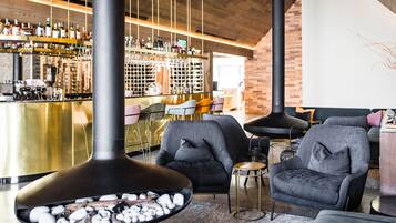 Uma área de bar moderna com diversas garrafas de bebidas, um balcão e assentos com lareira.