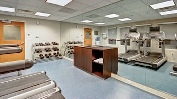 Centro de fitness com esteiras, halteres e um banco de musculação.