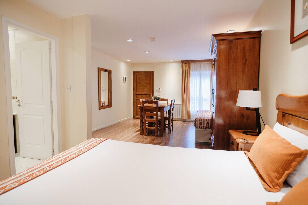 Quarto de hotel com cama, escrivaninha e cadeira.