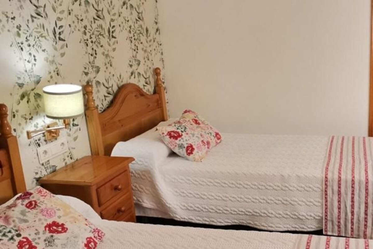 Quarto com duas camas, uma mesa de cabeceira, um abajur e área de chuveiro.