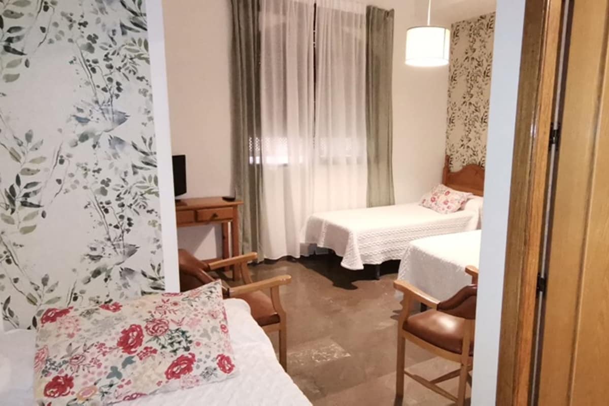 Quarto com uma cama de solteiro, mesa de cabeceira, uma cadeira e guarda-roupa.