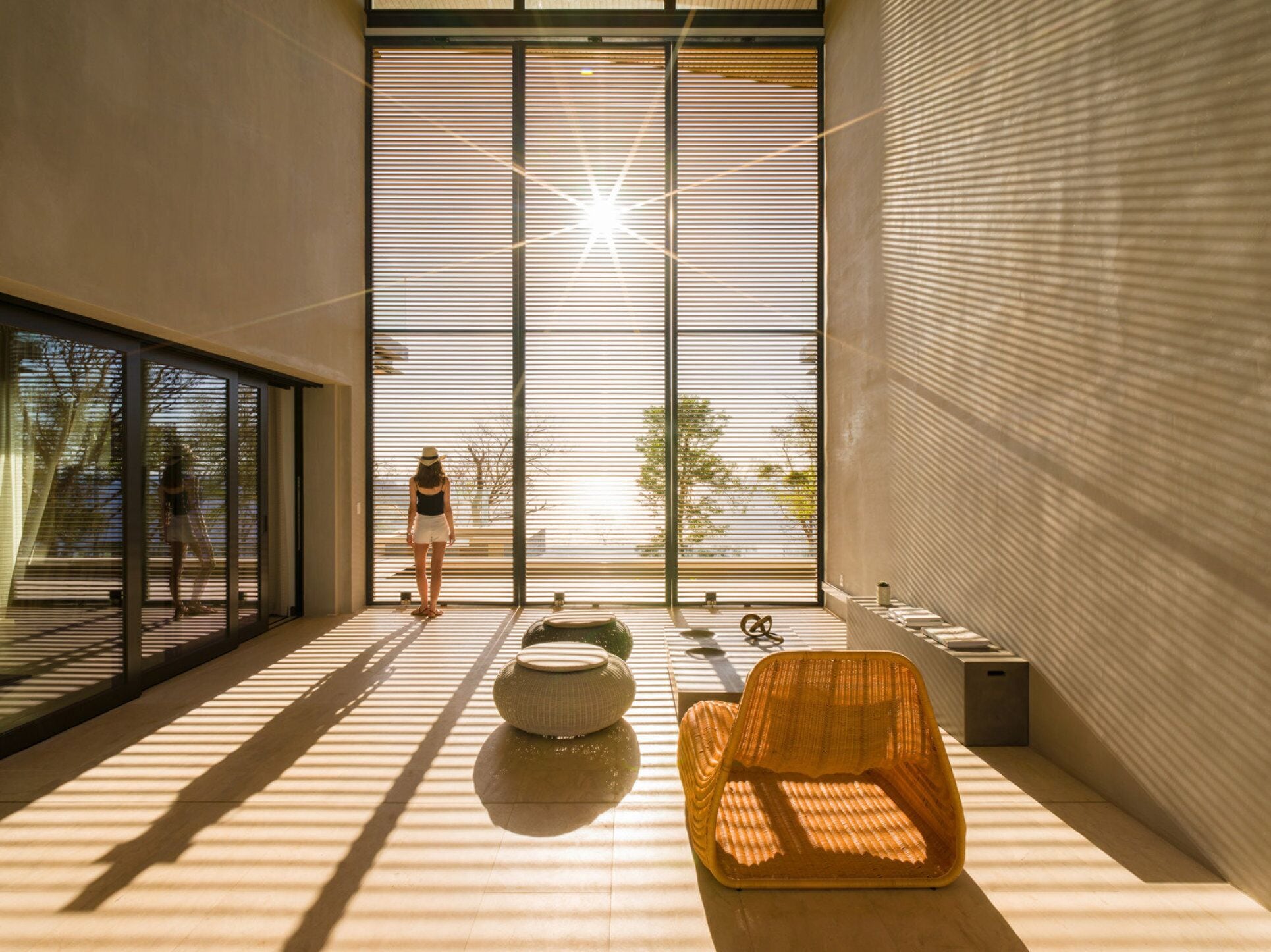 Um interior moderno com grandes janelas, uma área de estar central e vista para o exterior.