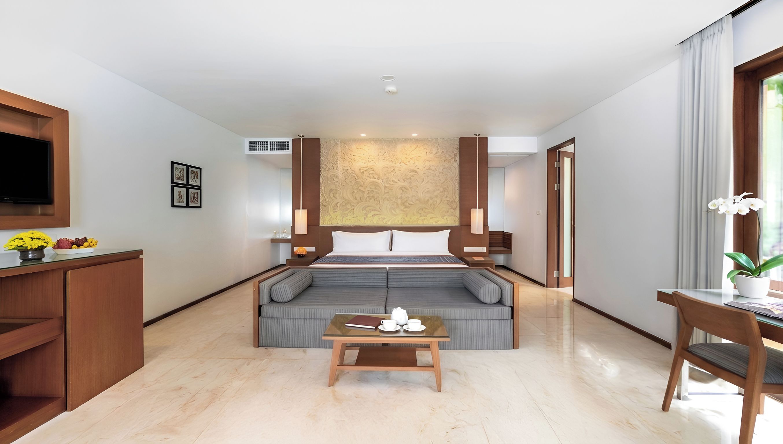 Quarto de hotel com cama, escrivaninha, televisão e janela com cortinas.