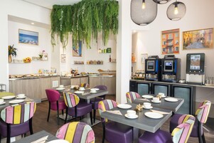 Interior de restaurante com mesas preparadas para refeições, área de bar e máquina de café.