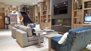 Uma sala de estar moderna com sofá, poltrona e mesa de centro. Escada com corrimão leva a um andar superior.