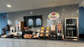 Uma mesa de pequeno-almoço com uma televisão de ecrã plano, um sinal a indicar 'Superstart breakfast' e um balcão refrigerado.