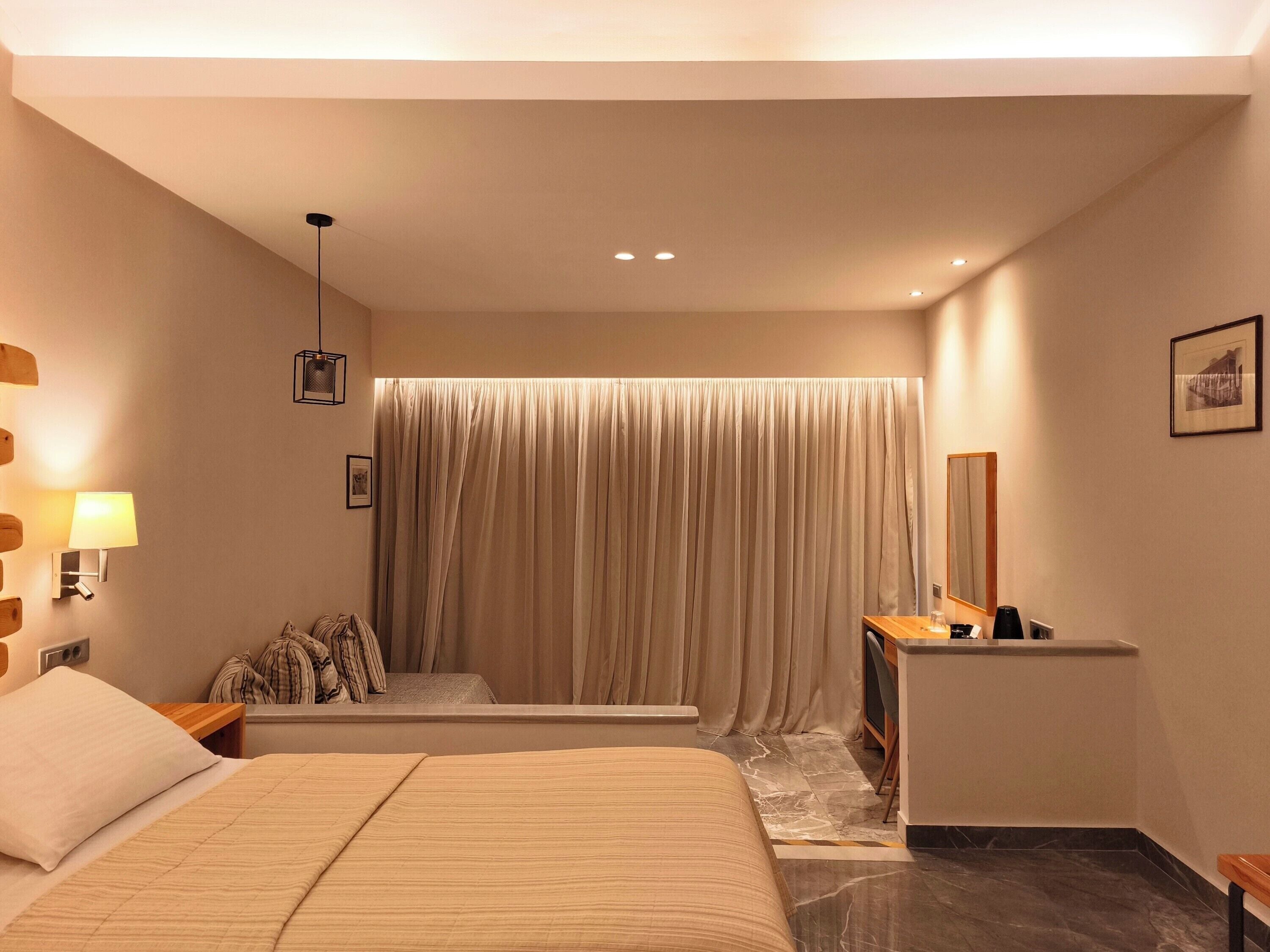 Quarto de hotel com cama, escrivaninha, espelho e cortina.