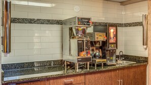 Uma cozinha comercial com máquina de café, dispensador de chocolate e jarra de café.