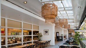 Um restaurante com tetos altos, mobiliário de vime e um espaço envidraçado.