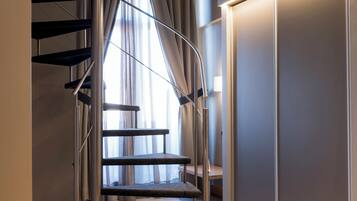 Um interior moderno com escadas de vidro que levam a um segundo andar, um guarda-roupa espaçoso e vista pela janela com cortinas.