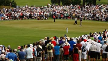 Um campo de golfe com uma grande multidão de espectadores.