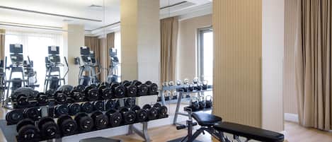 Uma academia com equipamentos de ginástica, espelhos e um banco.
