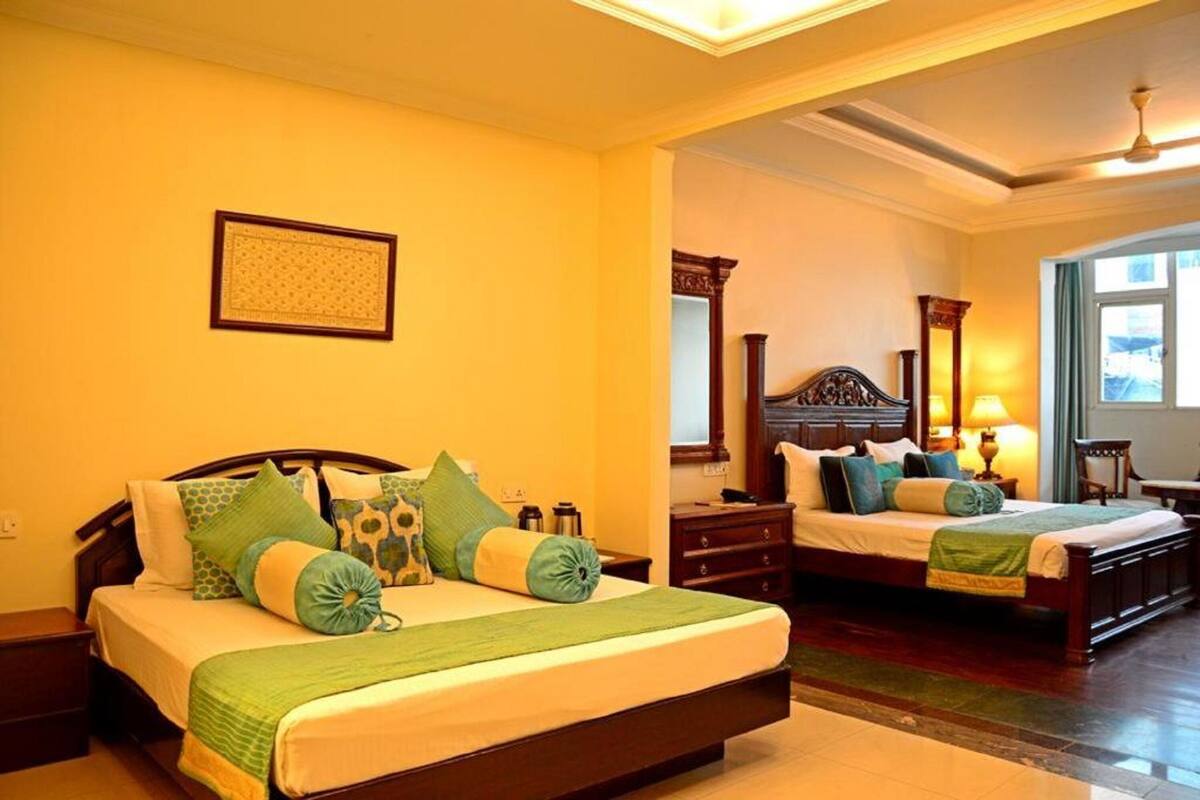 Quarto de hotel com uma cama grande, mesa de cabeceira, espelho e janela.