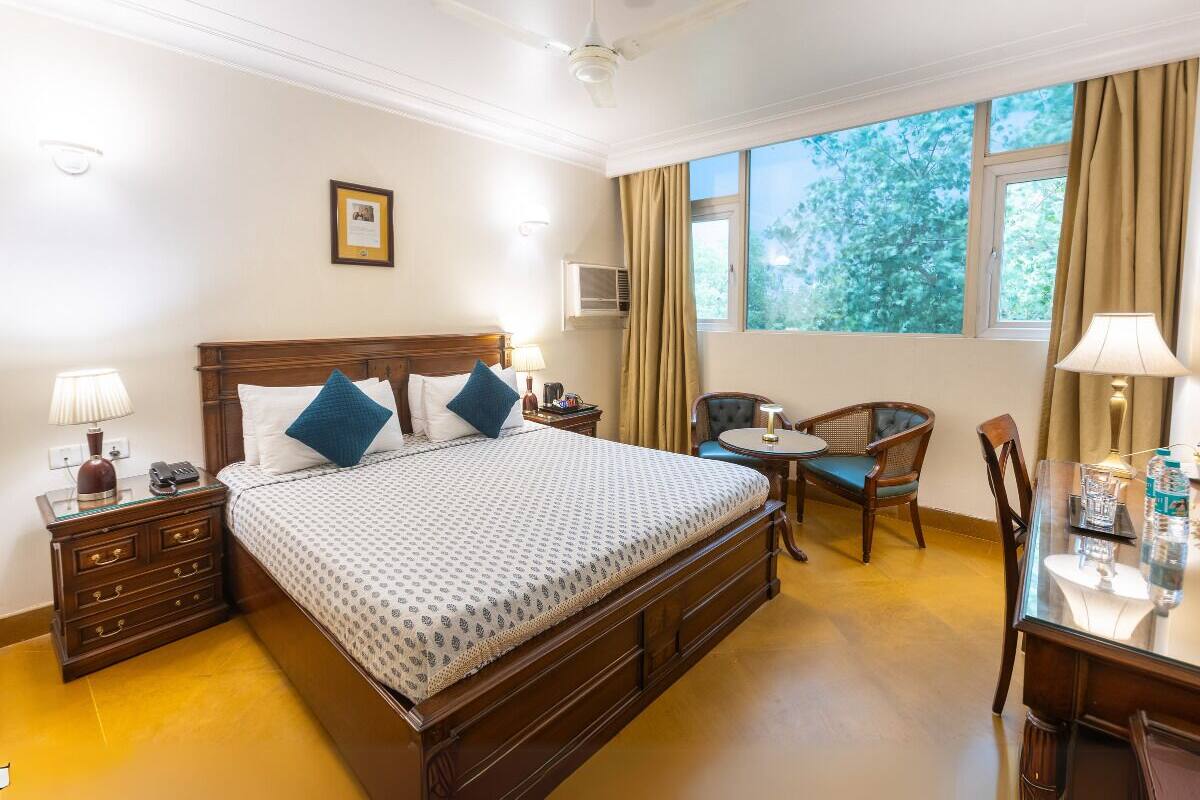 Um quarto bem organizado, com uma cama grande, mesas de cabeceira, uma escrivaninha e uma cadeira.