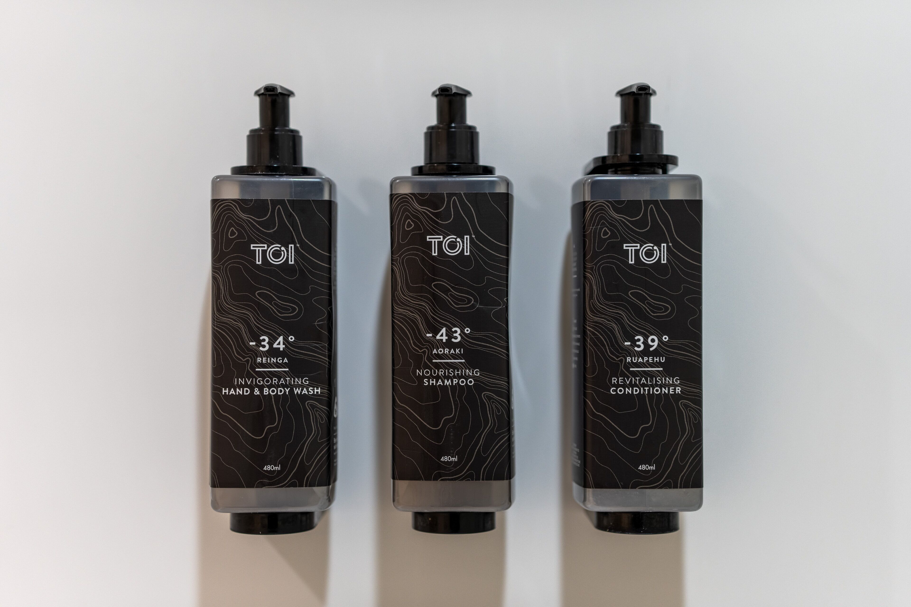 Três frascos de produtos TOI para o cabelo.