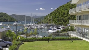 Uma marina com barcos, um espaço gramado e um edifício com varandas.