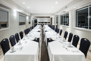 Uma sala de conferências com mesas compridas preparadas para uma reunião.