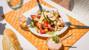 Uma salada de frutas com camarão, morangos, kiwi e pepino, sobre um sousbento de palha.