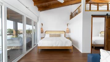 Quarto com cama de madeira, ventoinha no teto e vista através de grandes portas de vidro.
