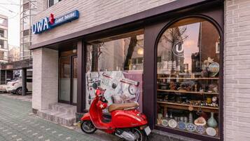 Um edifício com uma placa que diz 'UWA Guest House' e uma scooter vermelha estacionada na frente.