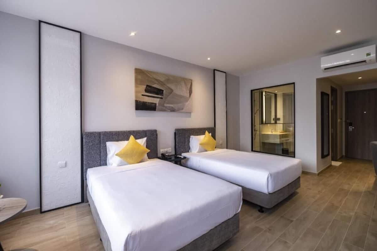 Quarto de hotel com duas camas, um espelho, um quadro e um ar condicionado.