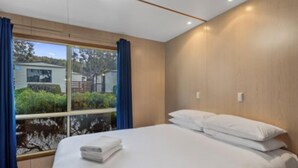 Quarto com cama grande, janela com cortinas e vista para o exterior.