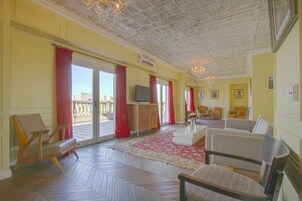Uma sala de estar ampla com uma grande janela, um candelabro e uma televisão.