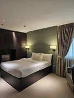 Quarto moderno com uma cama grande, guarda-roupa de madeira escura, duas luminárias de cabeceira e vista para o exterior através de uma janela com cortinas.