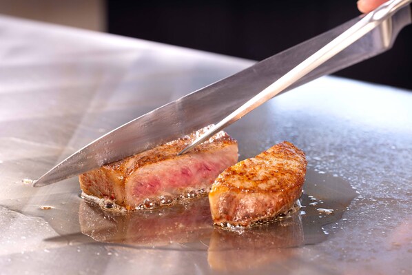 Um bife sendo fatiado em uma tábua de corte.