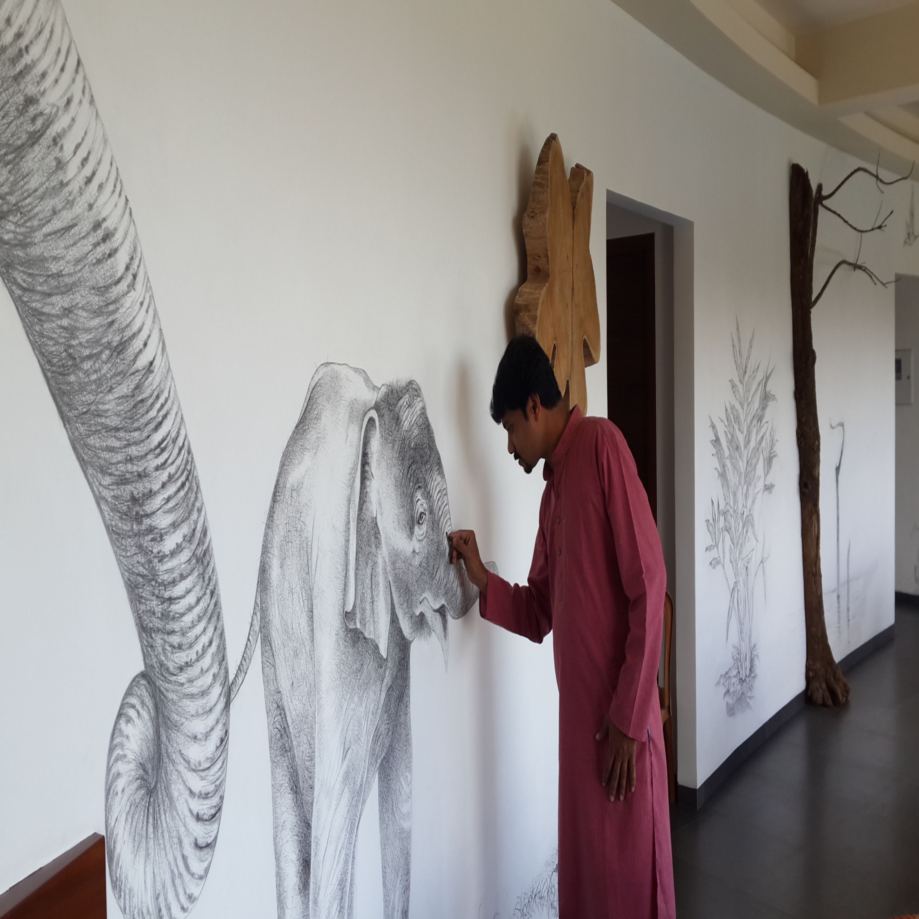 Uma pessoa desenhando um elefante detalhado numa parede.