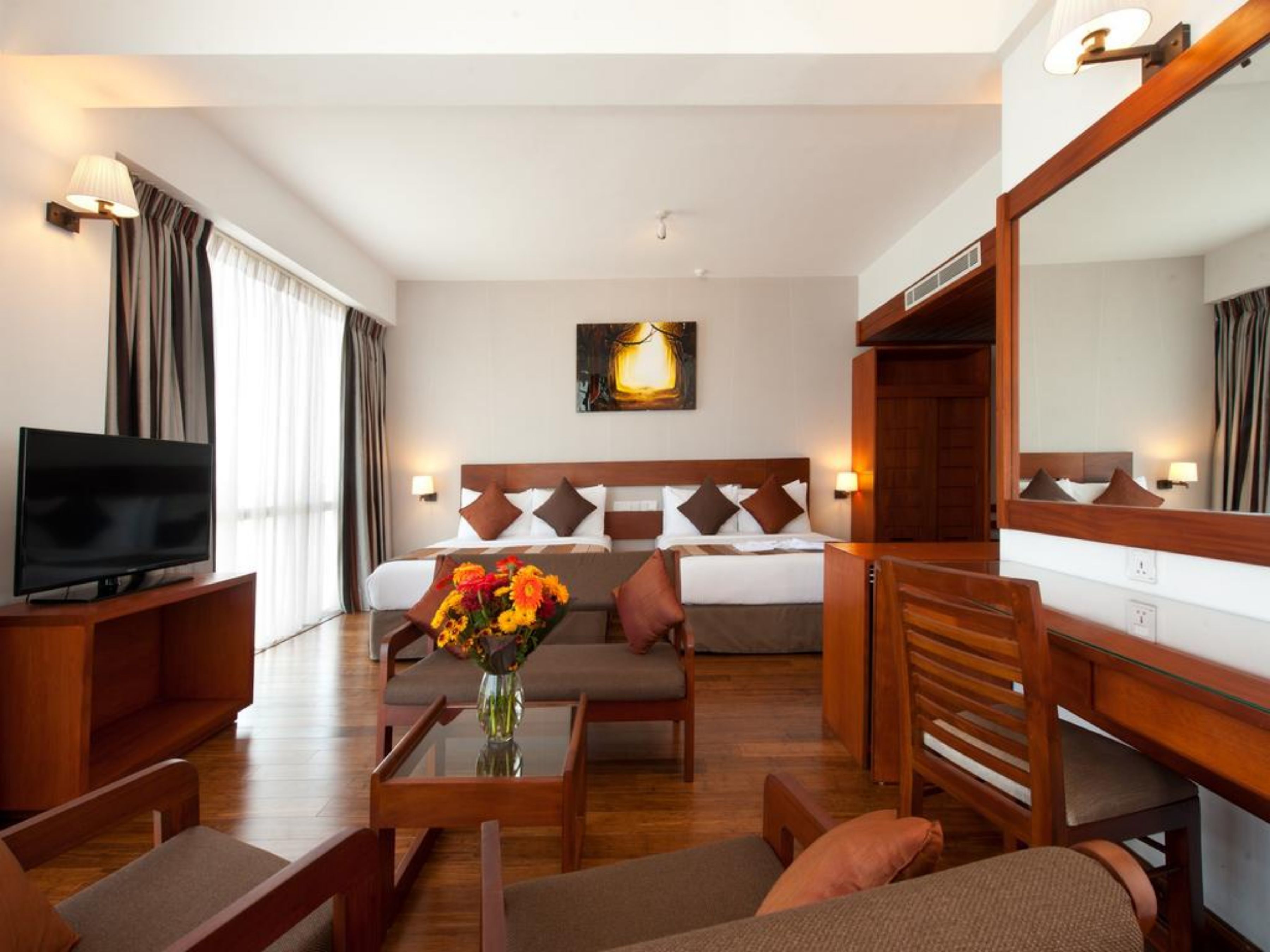 Quarto de hotel com uma cama, televisão, escrivaninha e sofá.