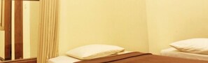Quarto pequeno com uma cama de solteiro, cabeceira de madeira, parede bege e janela com persianas verticais.