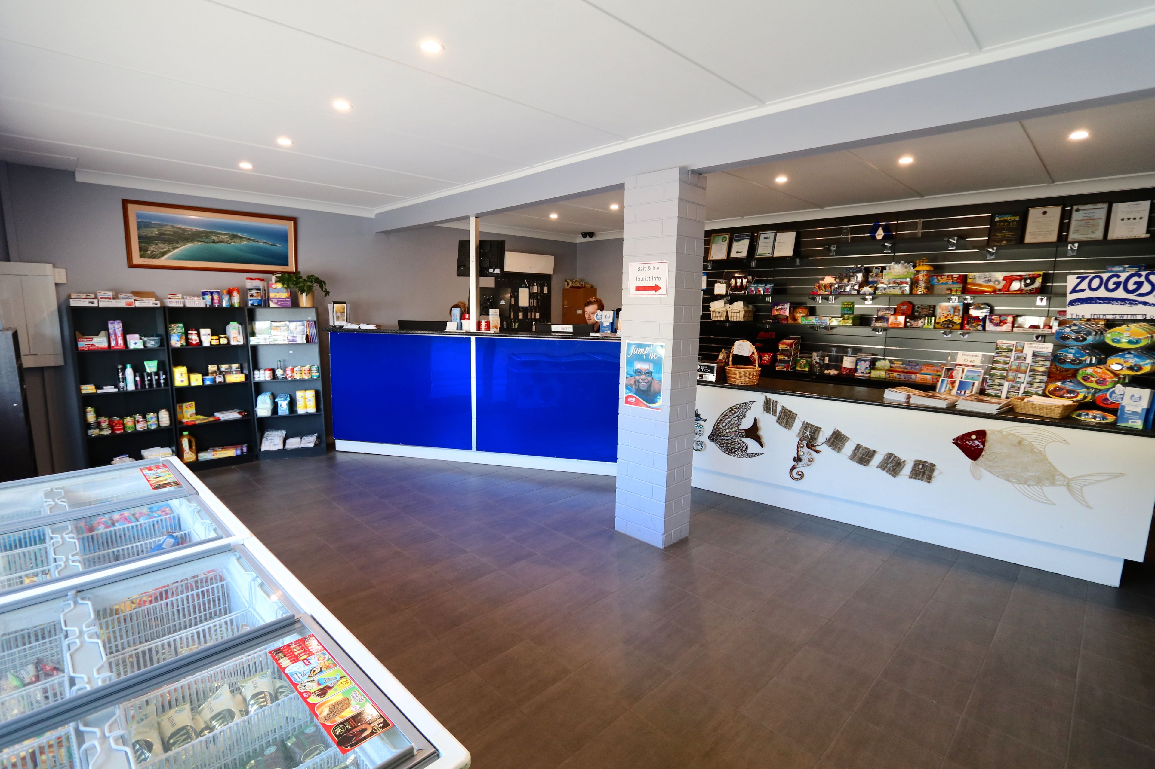 Restaurante de frutos do mar com balcão azul, vitrines refrigeradas e prateleiras repletas de diversos produtos do mar.