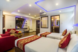 Quarto de hotel com duas camas, uma escrivaninha, uma cadeira e uma televisão.