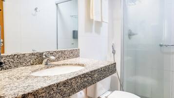 Um banheiro moderno com bancada de granito, vaso sanitário branco e box de vidro.