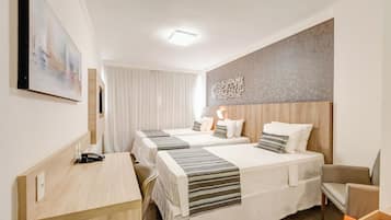 Quarto de hotel com duas camas, uma escrivaninha e uma cadeira.