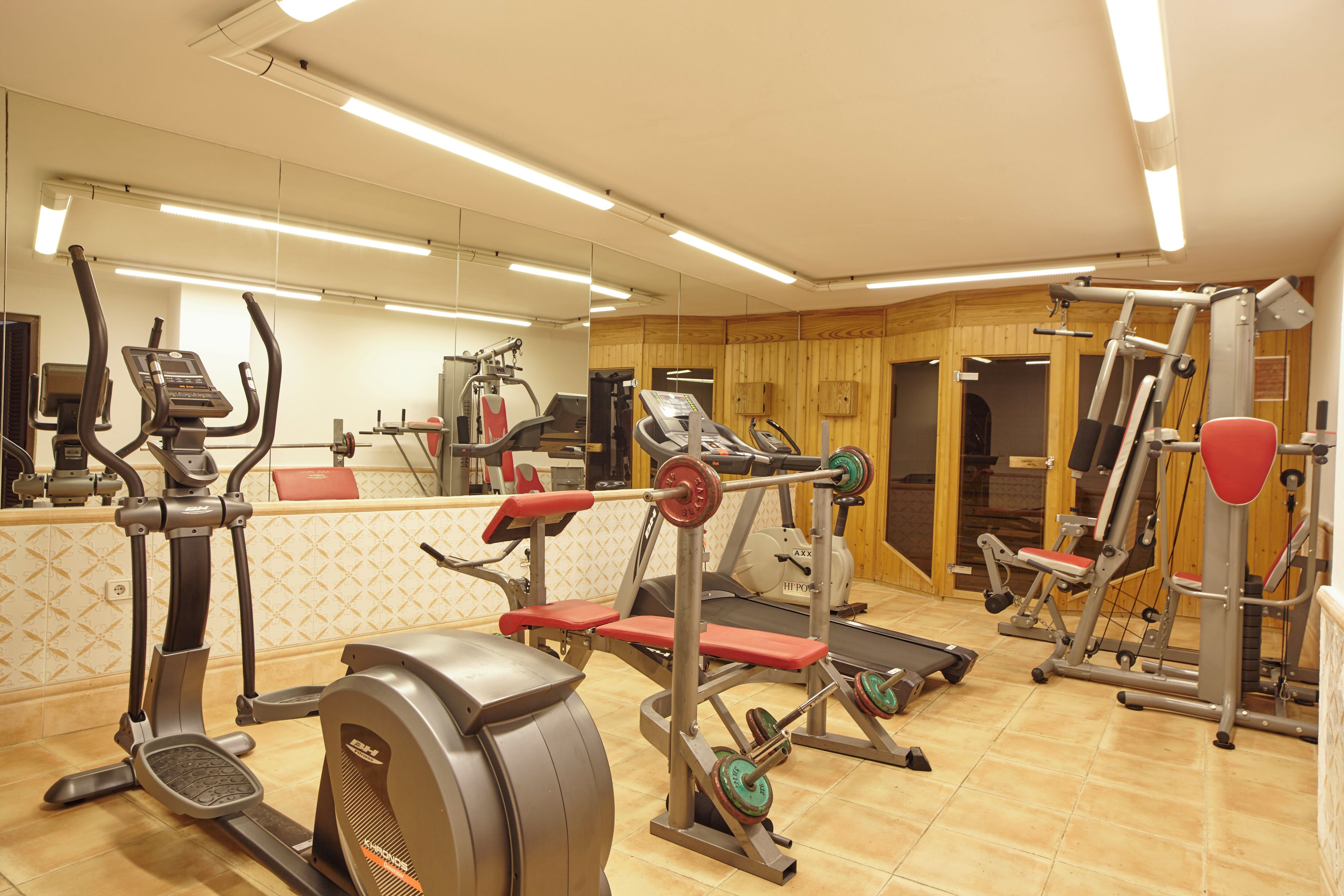 Academia com diversos equipamentos de ginástica, incluindo esteiras, máquinas de musculação e pesos livres.