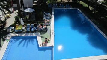 Piscina com espreguiçadeiras e guarda-sóis.