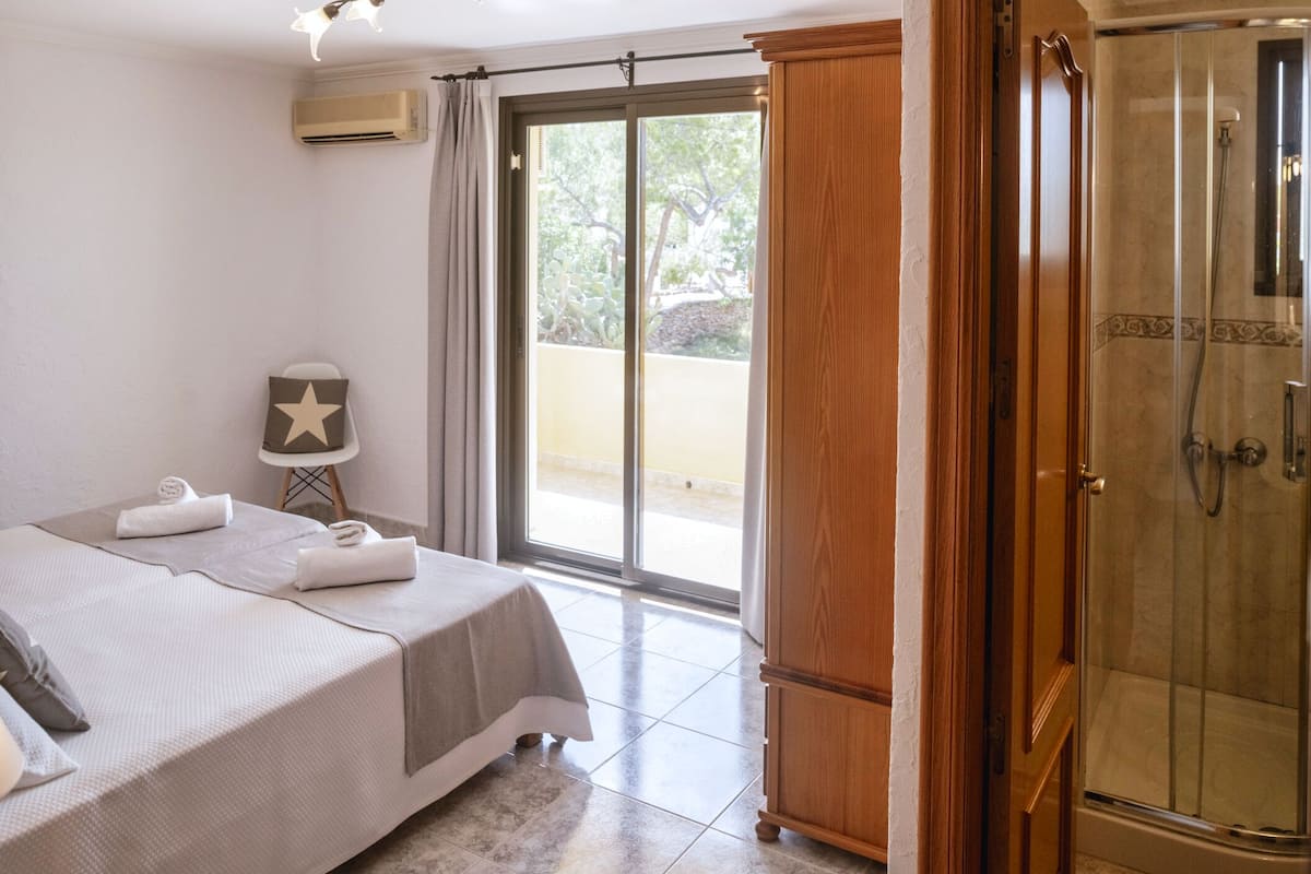Quarto de hotel com cama, poltrona, travesseiro com formato de estrela, chuveiro e vista para o exterior.