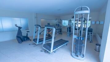 Academia moderna com aparelhos de cardio, estações de musculação e um espelho grande.