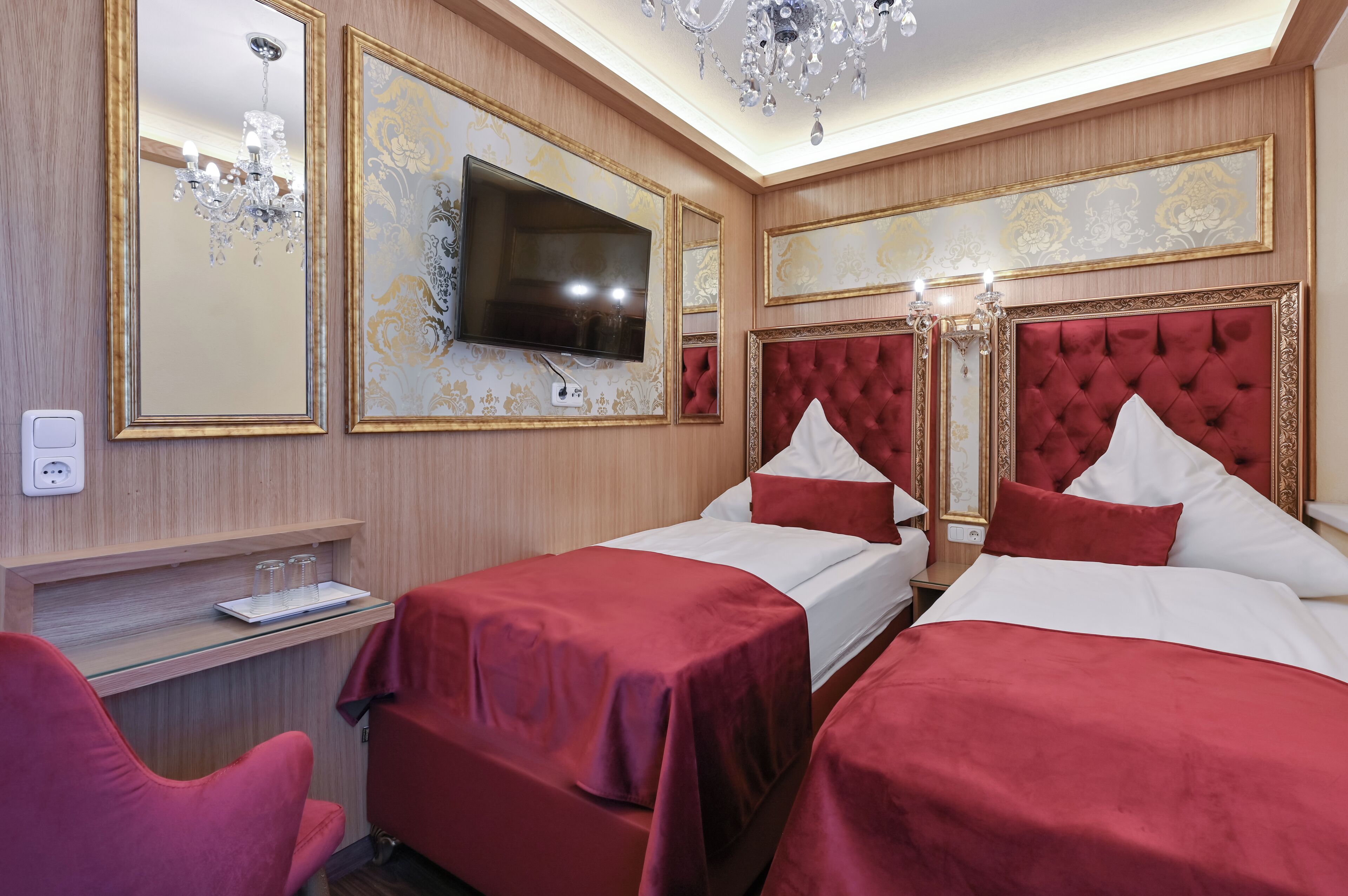 Quarto de hotel com duas camas, televisão, secretária e uma cadeira.