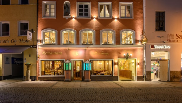 Hotel com várias áreas de refeições, entrada visível e placa indicando uma pizzaria próxima.