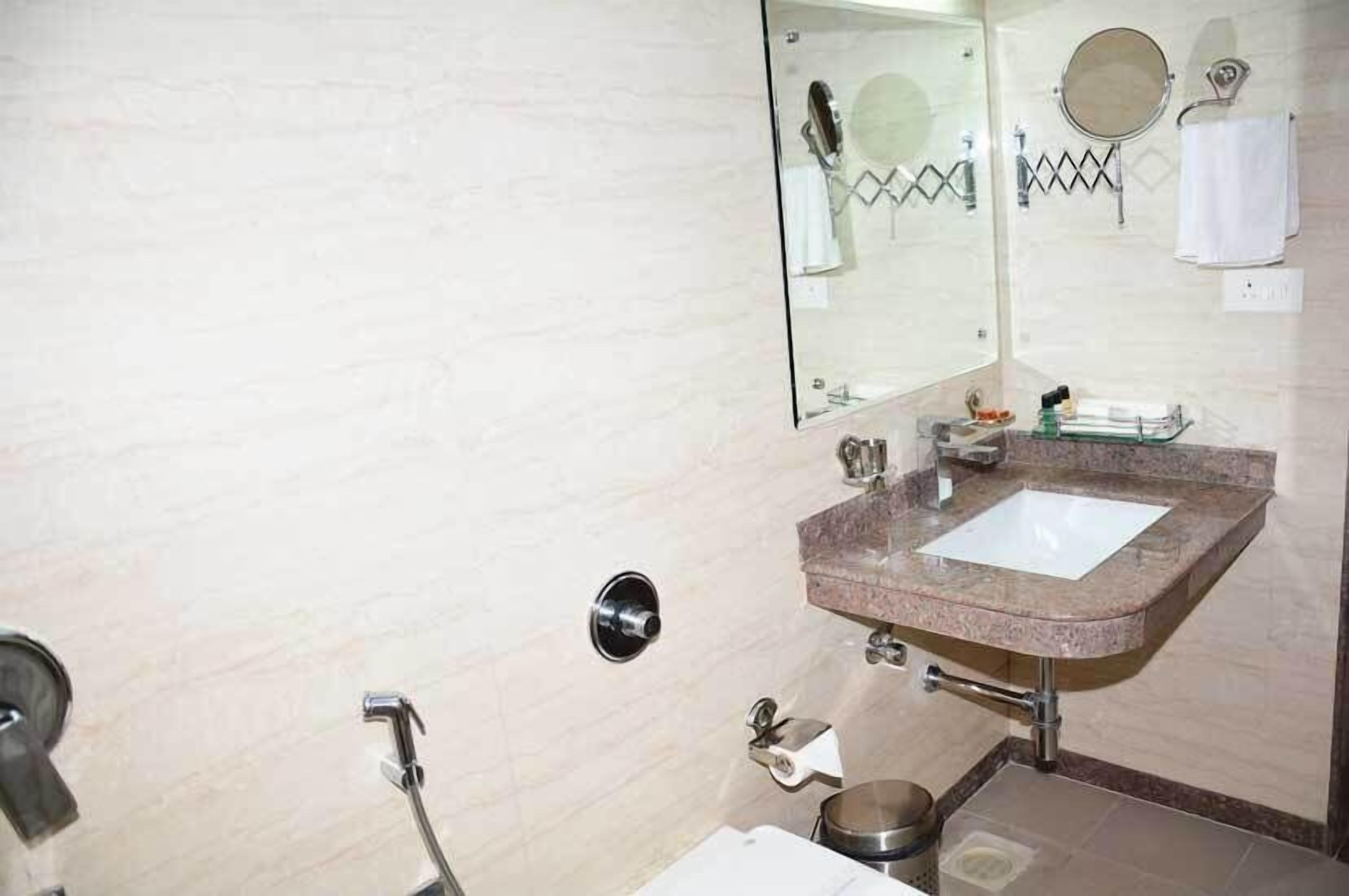 Um banheiro com pia de mármore, espelho, porta-toalhas e vaso sanitário.