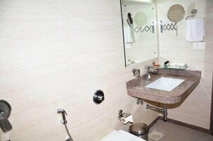 Um banheiro com pia de mármore, espelho, porta-toalhas e vaso sanitário.