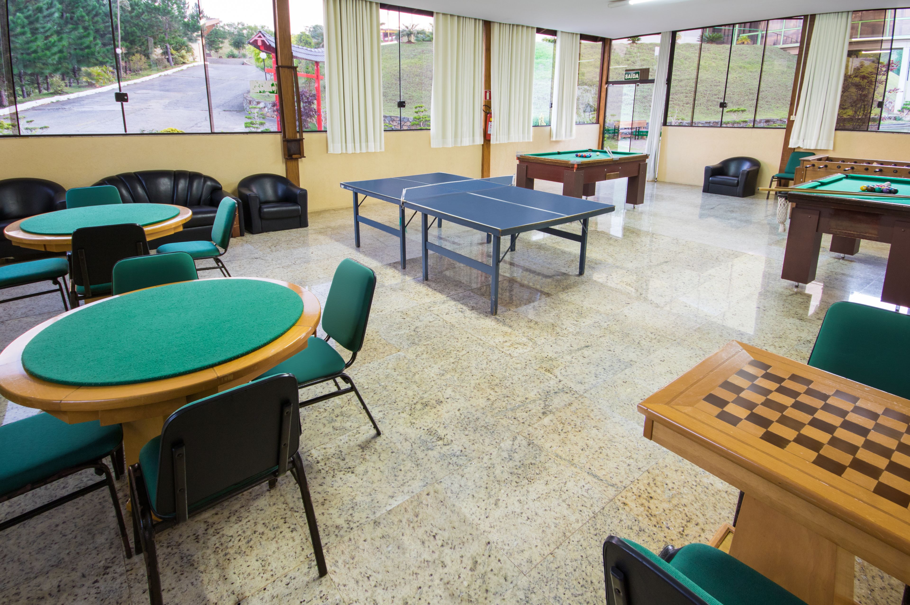 Uma sala de lazer com mesas de pingue-pongue, mesas de bilhar e uma mesa de xadrez.